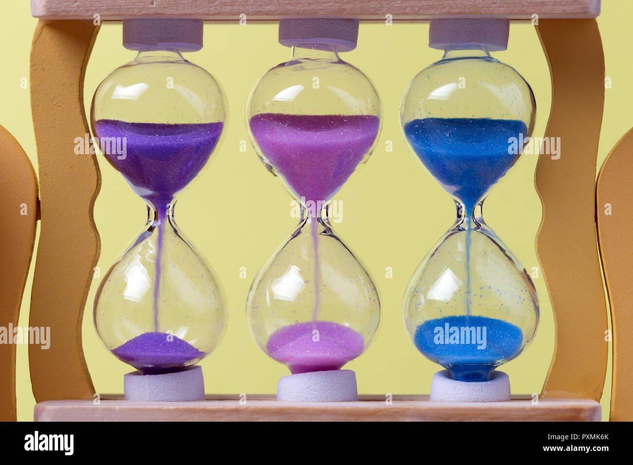 colored hourglass on the background of the yellow wall Stock Photo - Alamy