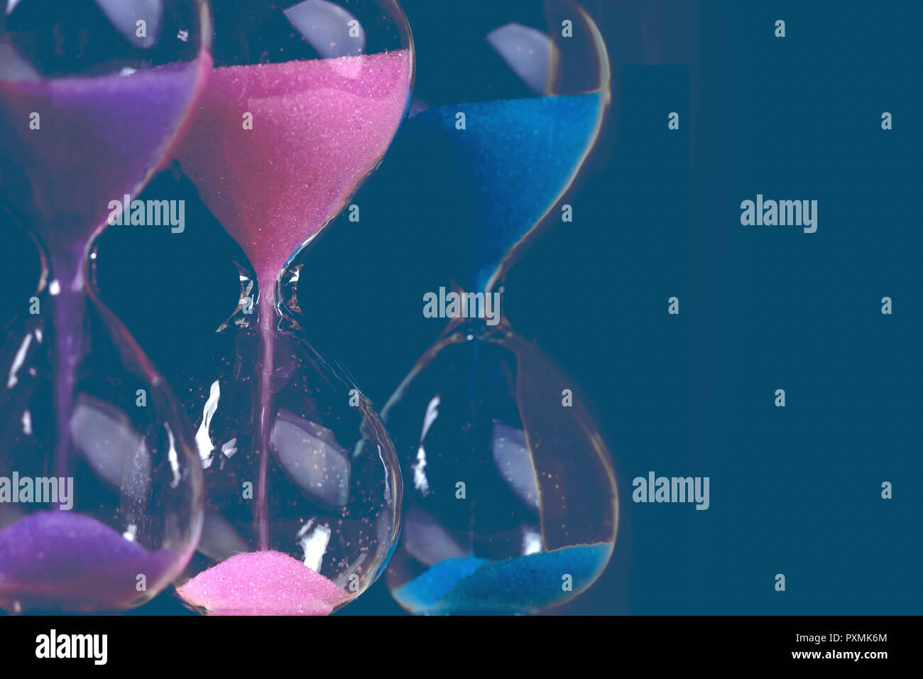 colored hourglass on a blue wall background, toned image Stock Photo ...