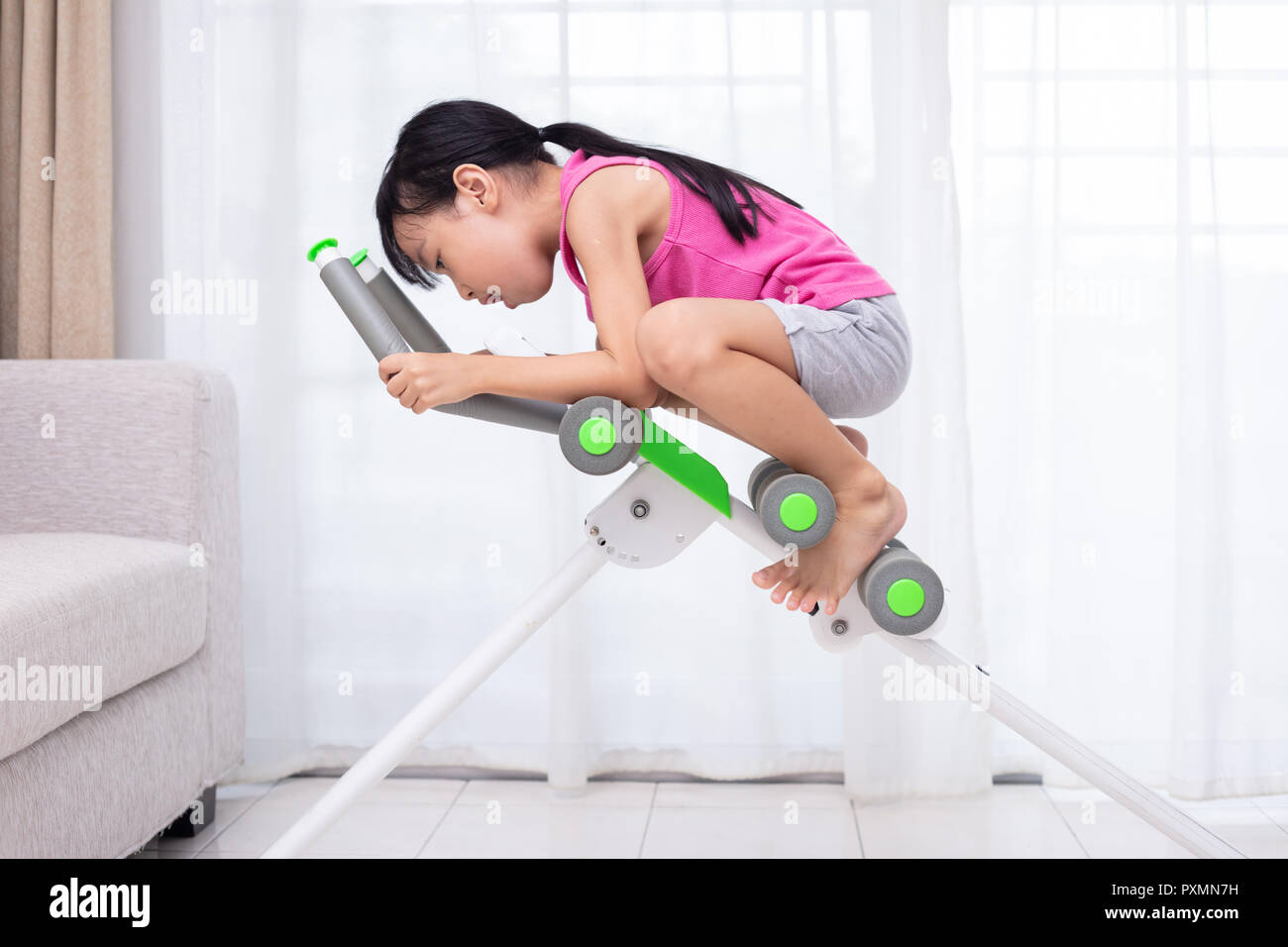 Asian Chinese little Girl playing workout machine in the living room at ...