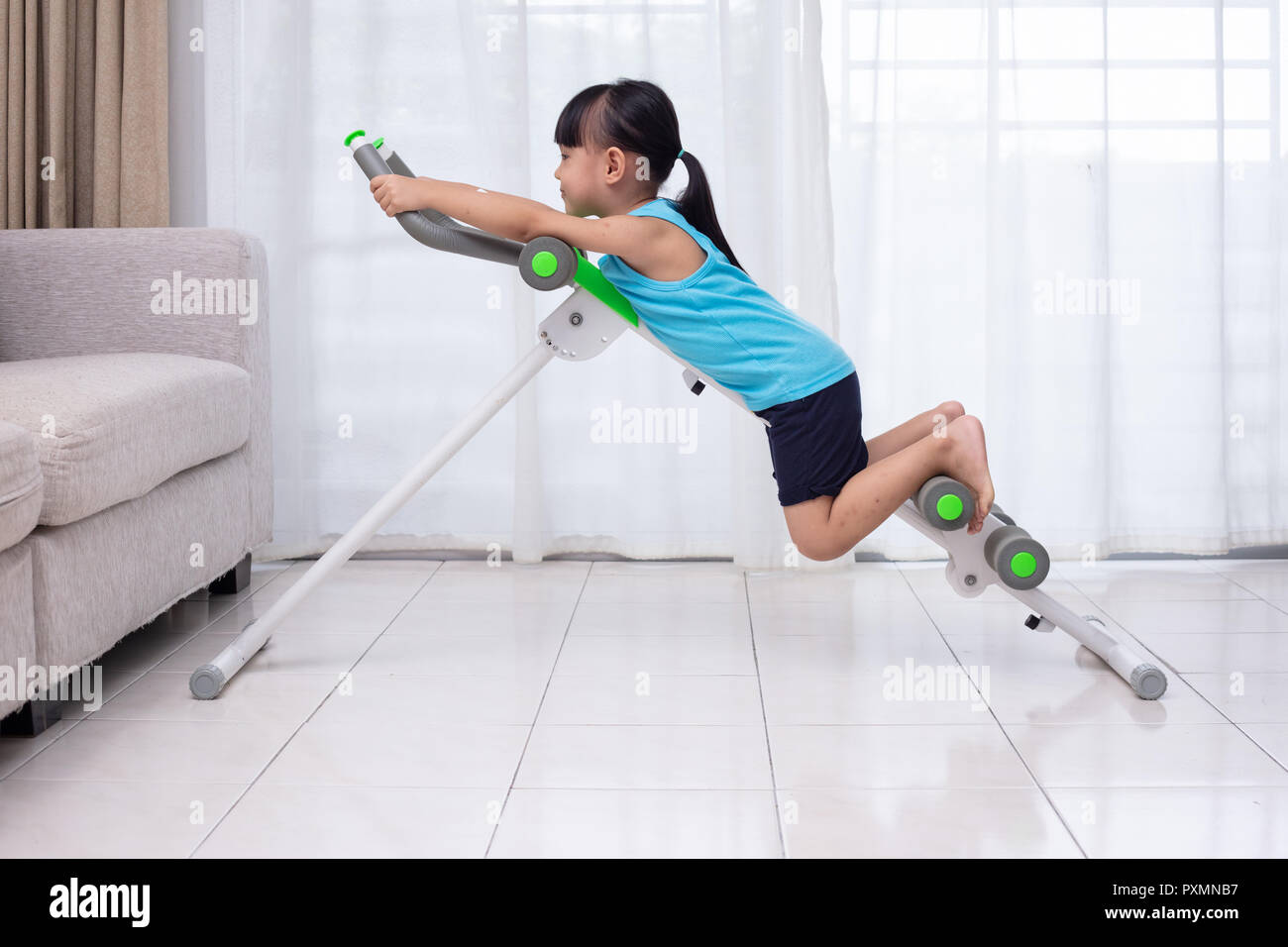 Asian Chinese little Girl playing workout machine in the living room at ...