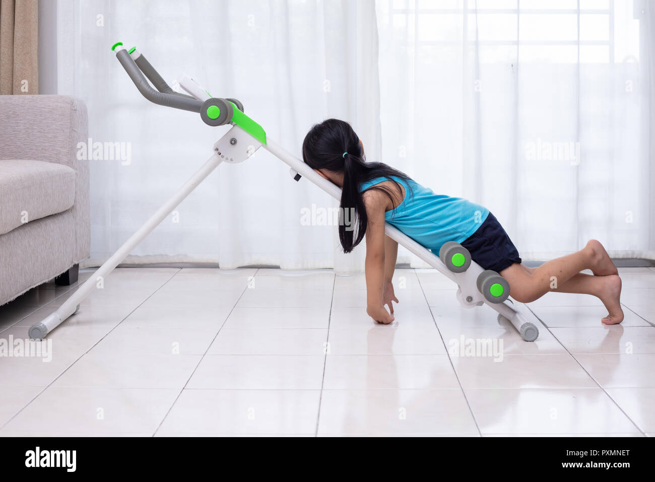 Asian Chinese little Girl playing workout machine in the living room at ...