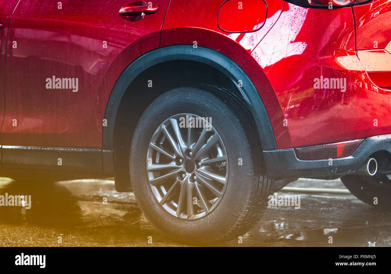 Red compact SUV car with sport design are washing with water. Car care ...
