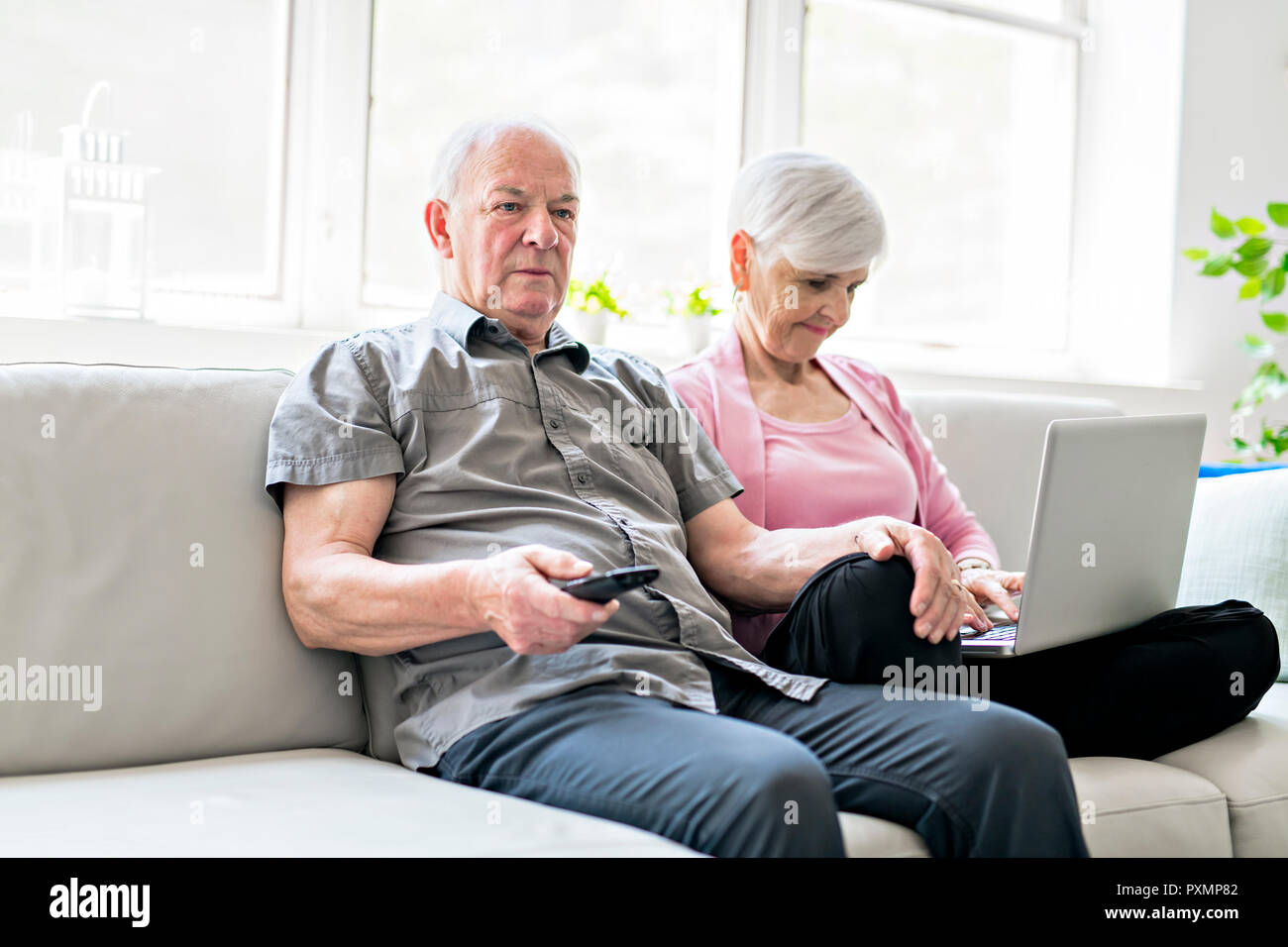Affectionate attractive elderly couple sitting together on a couch ...