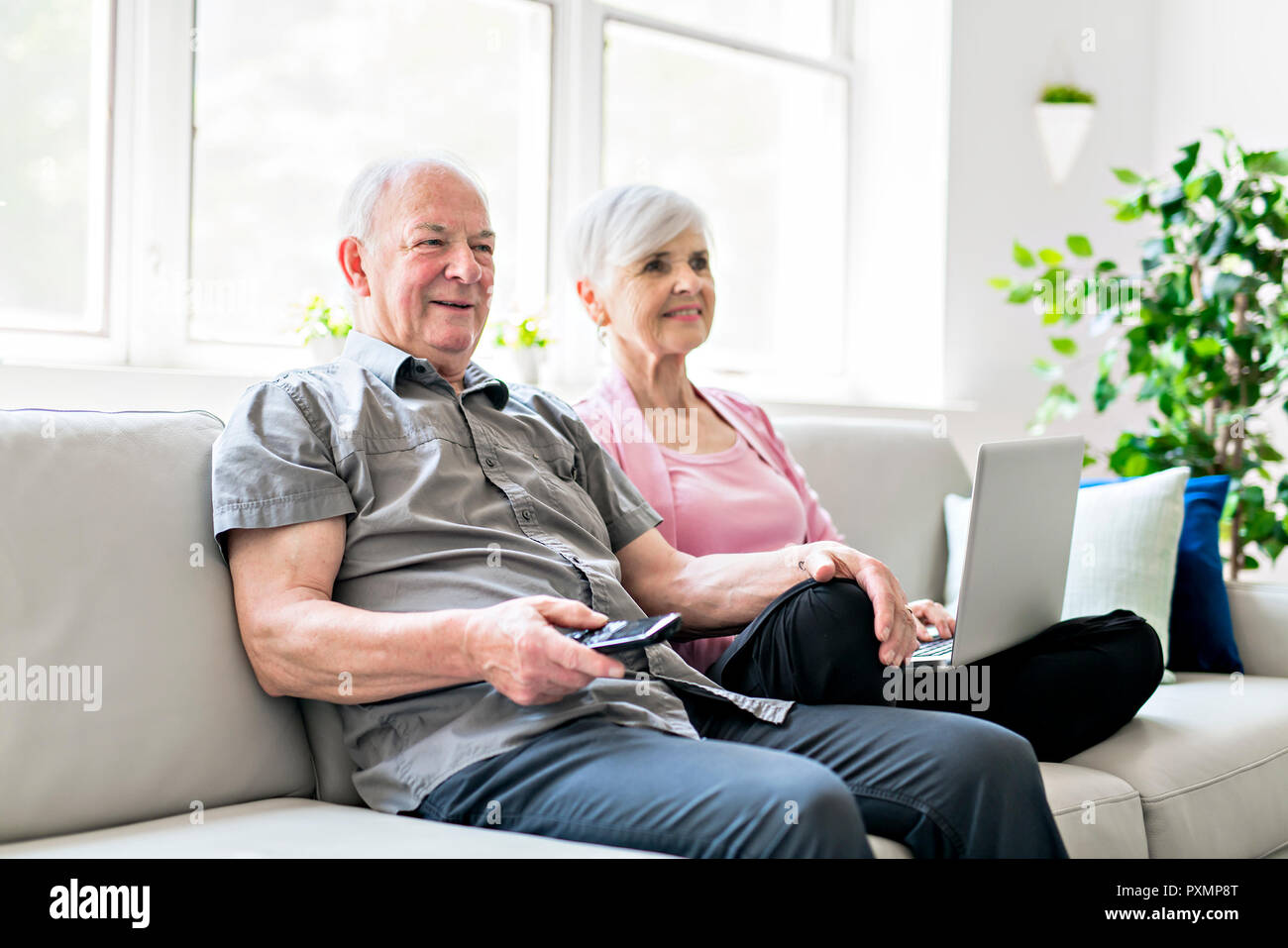 Affectionate attractive elderly couple sitting together on a couch ...
