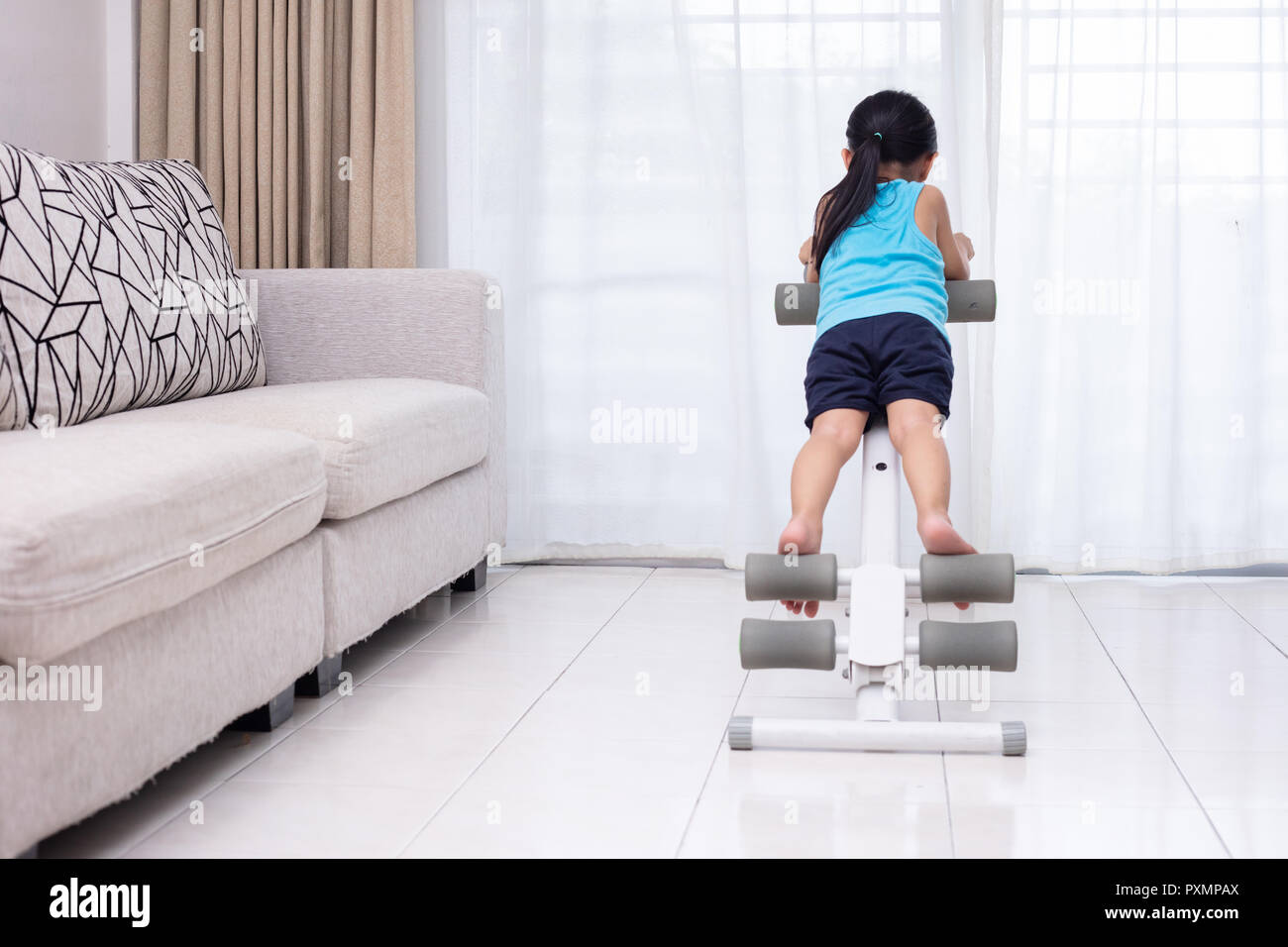 Asian Chinese little Girl playing workout machine in the living room at ...