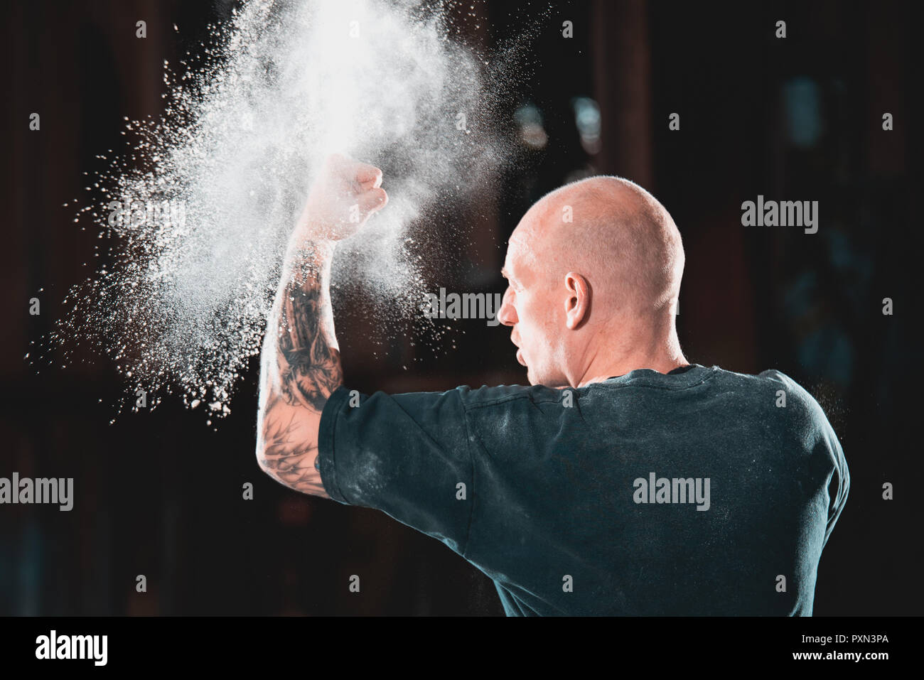 Male MMA Martial Artist fighter performing a upper cut punch with flour ...