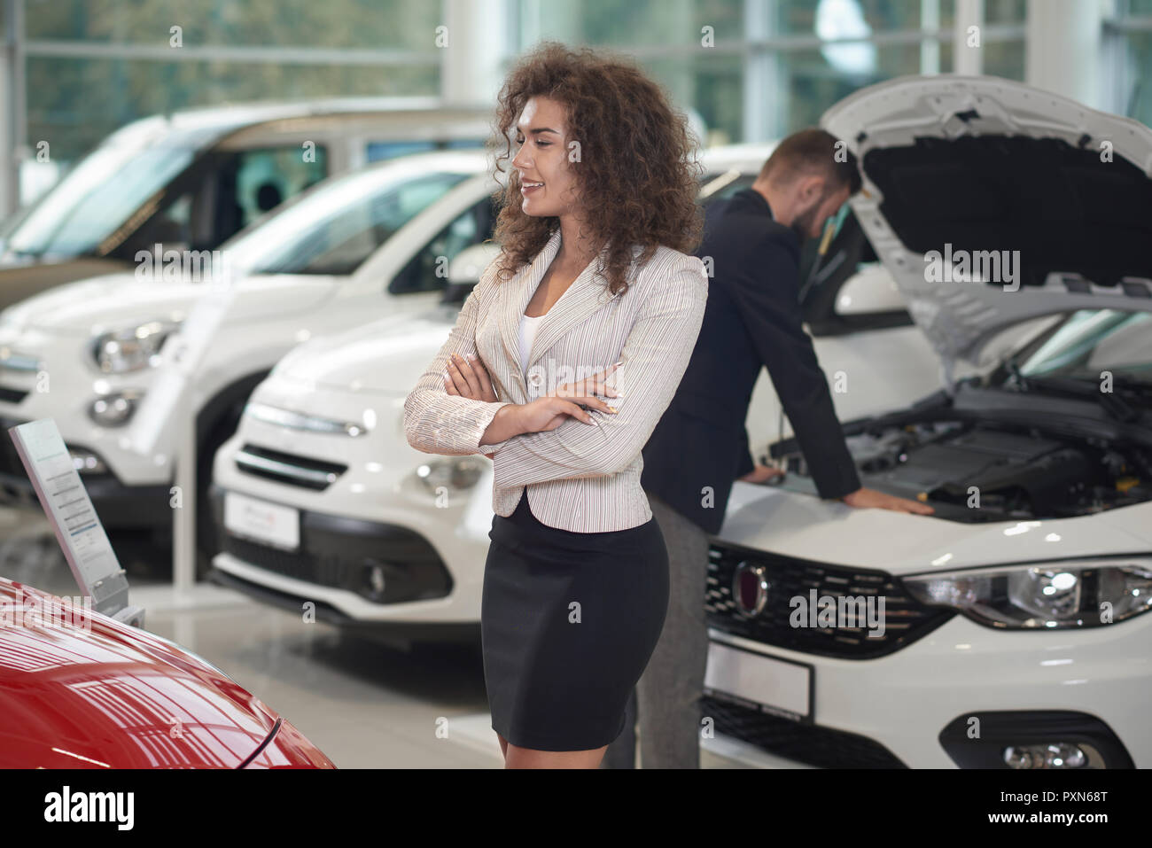 Curled happy woman walking in car store, when dealership looking inside ...