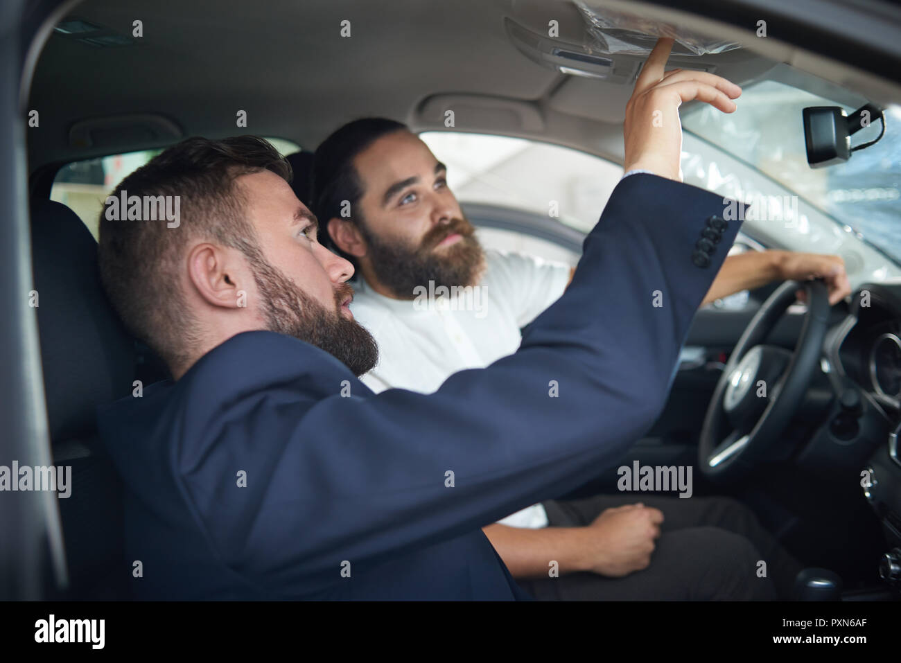 Customer of car dealership sitting on driver's seat and holding hand on ...