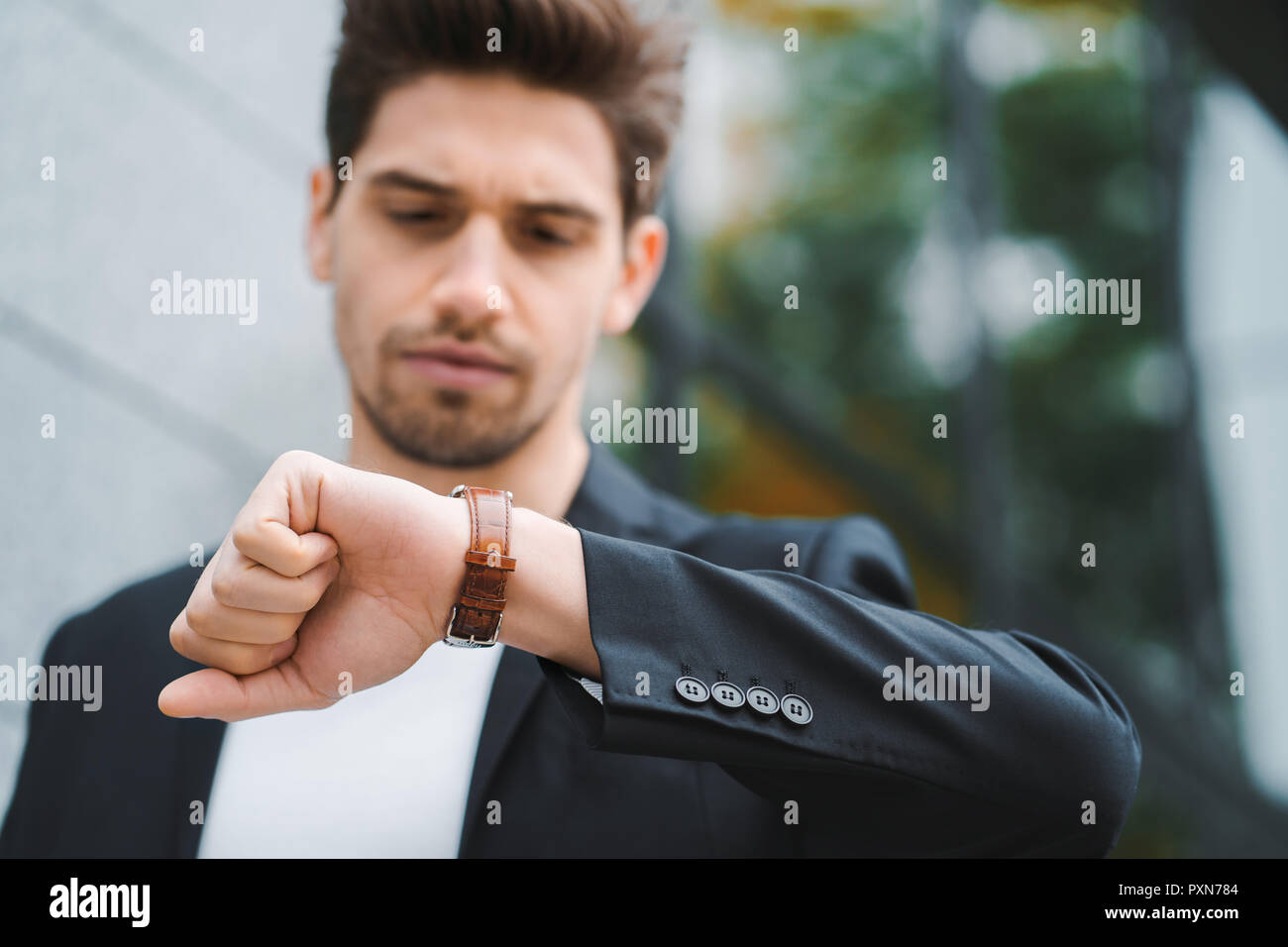 Handsome businessman or student looks at watch. Young man in hurry late ...