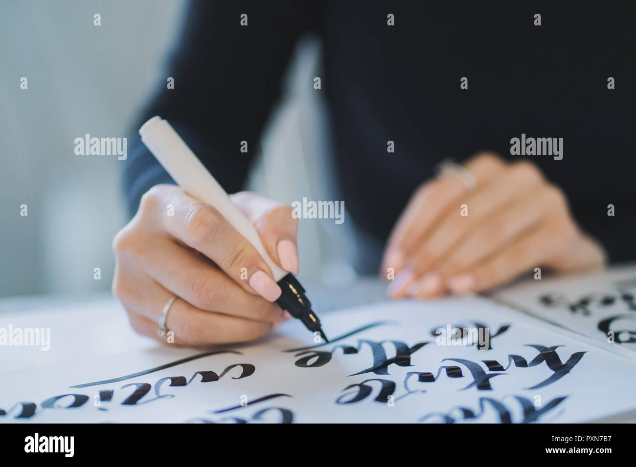 Calligrapher hands writes phrase on white paper. Inscribing ornamental ...
