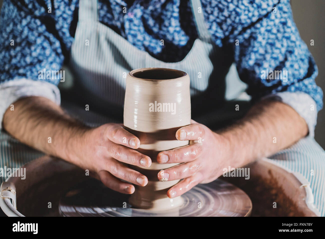 View of man making pot on pottery wheel. Potter shapes the clay product ...