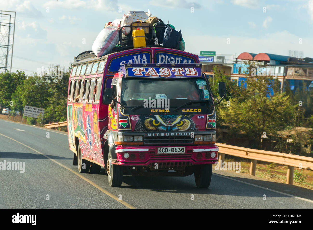A large colourful bus drives along a stretch of Mombasa road, Kenya ...