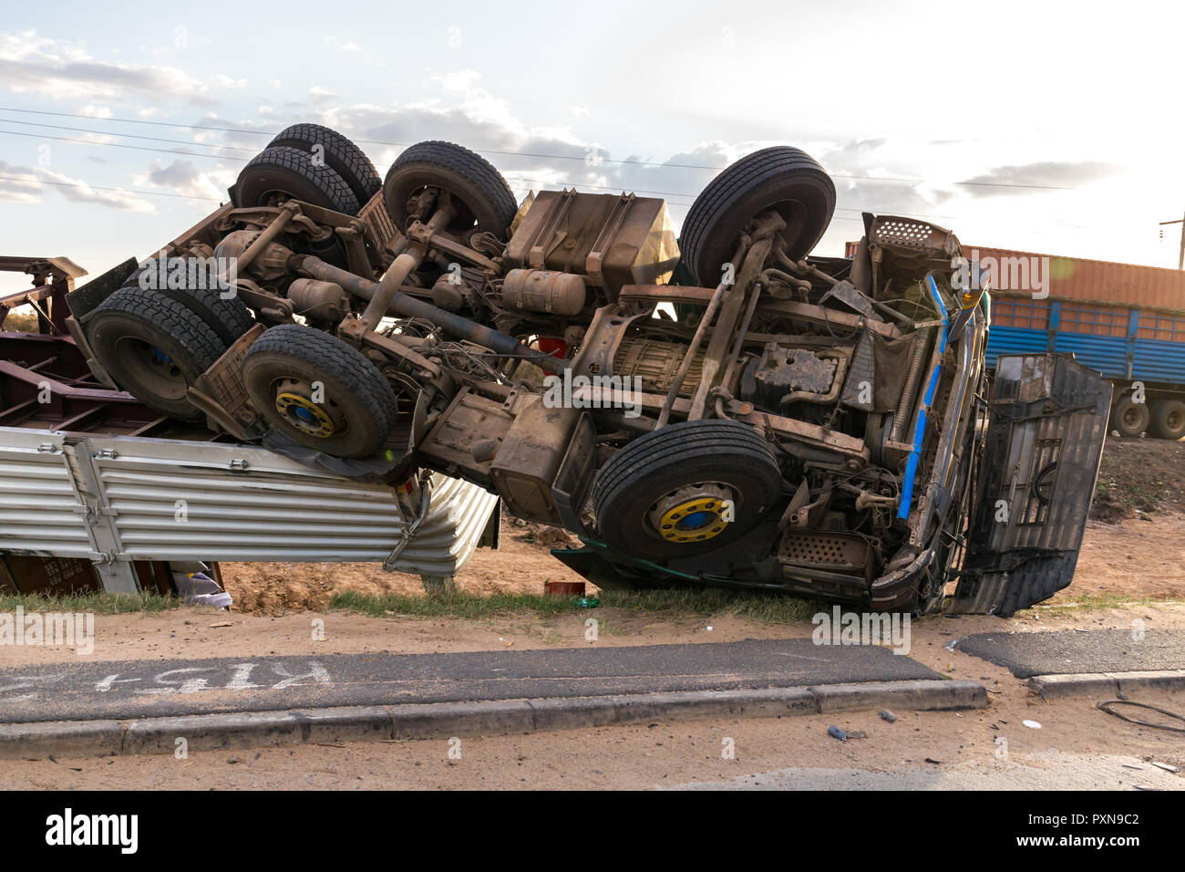 An overturned lorry by the side of the road with wheels in the air ...