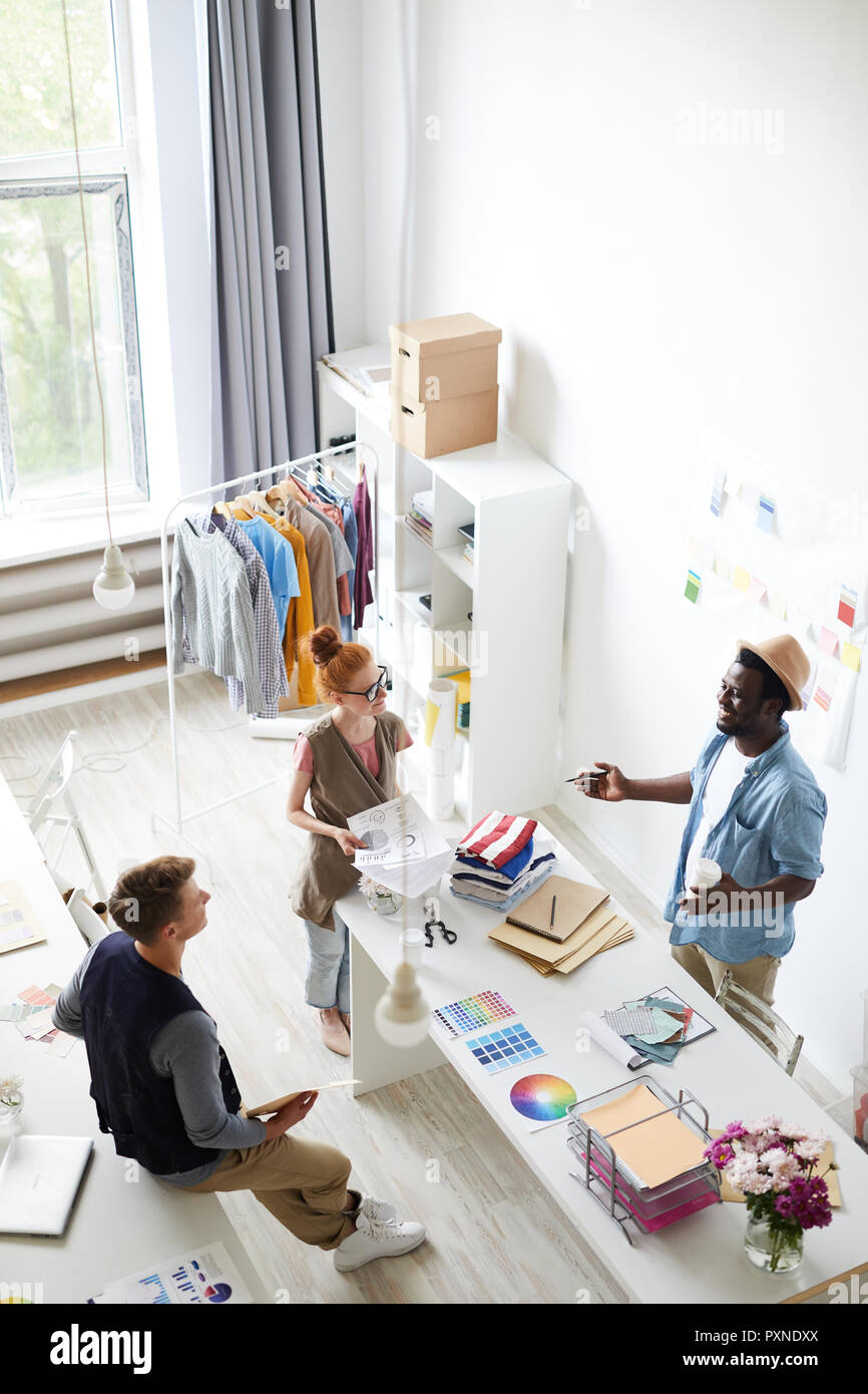 Multiethnic group of young designers standing around the table and ...