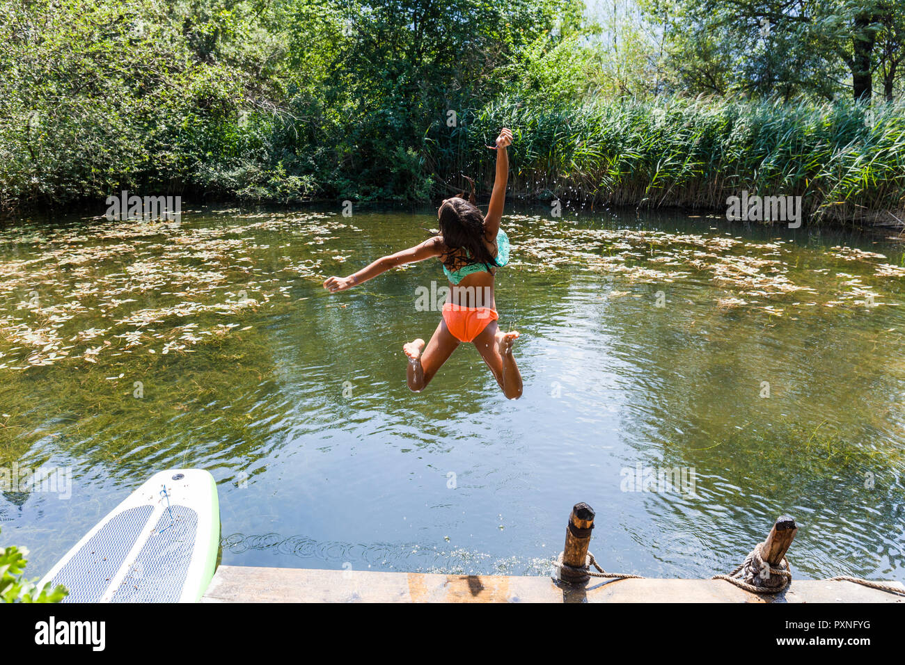 Carefree girl jumping into pond Stock Photo - Alamy