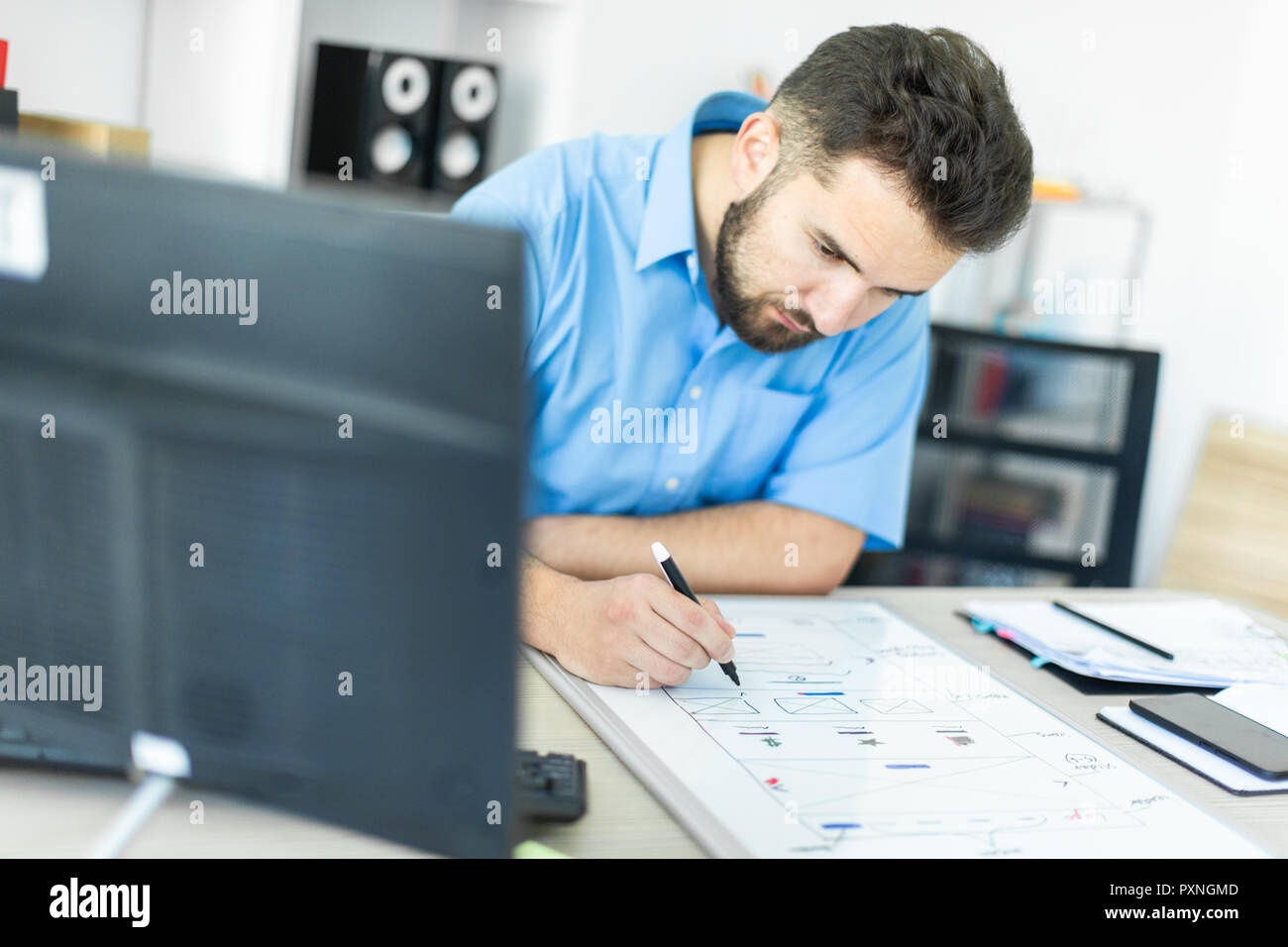 A smart young man works in a bright office. He has a neat beard. A ...