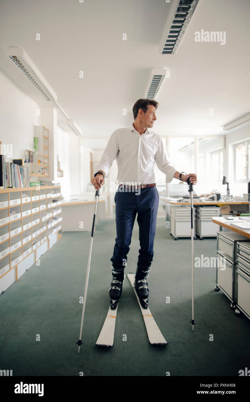 Businessman skiing in office Stock Photo - Alamy