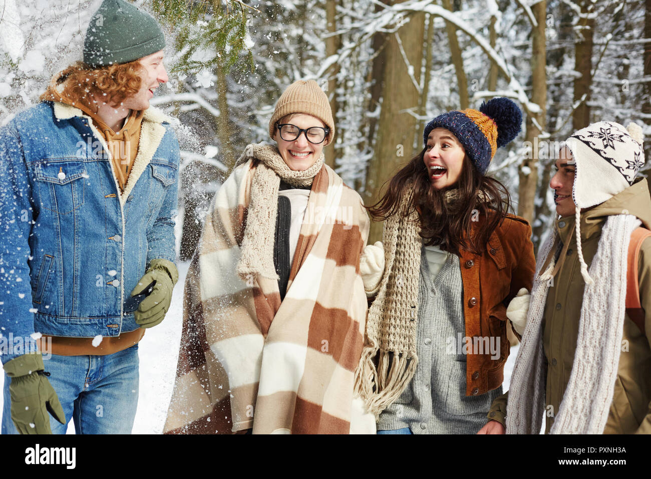 Group of modern young people having fun in winter forest playing with ...