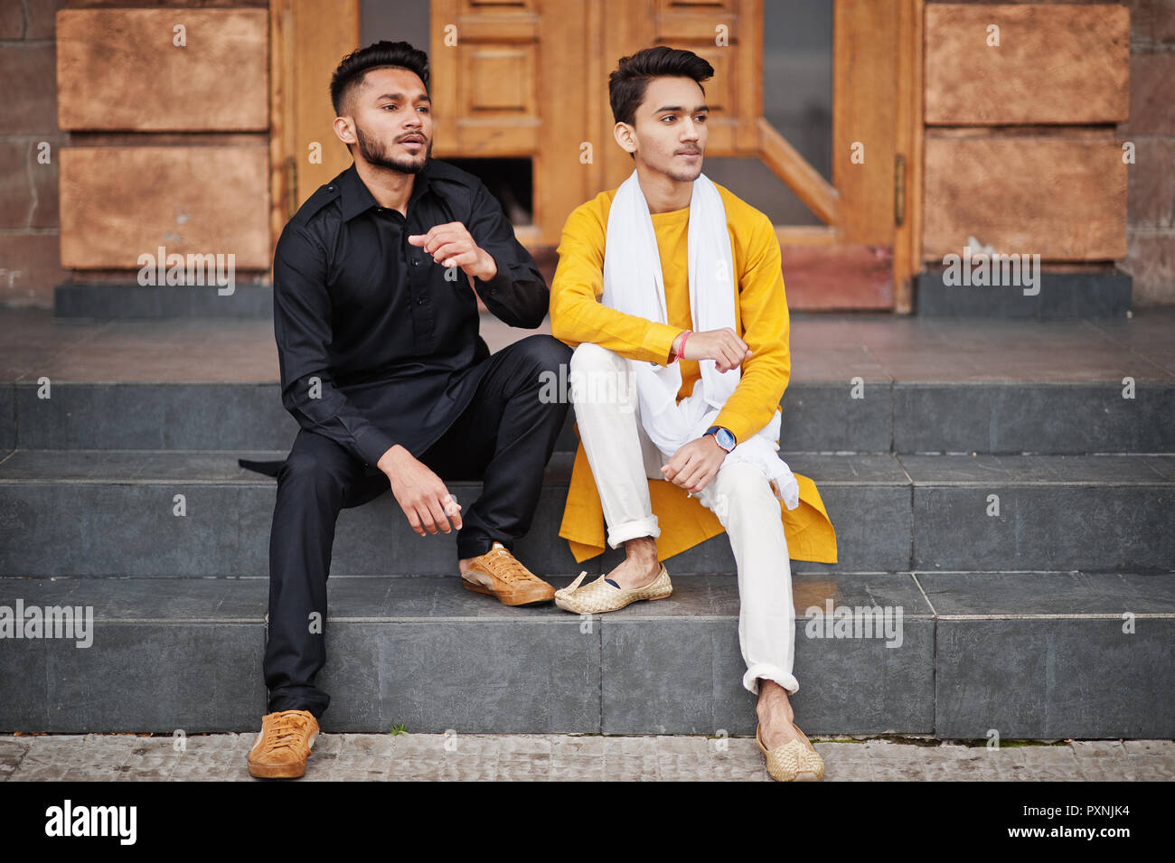 Two indian stylish mans friends in traditional clothes posed outdoor ...