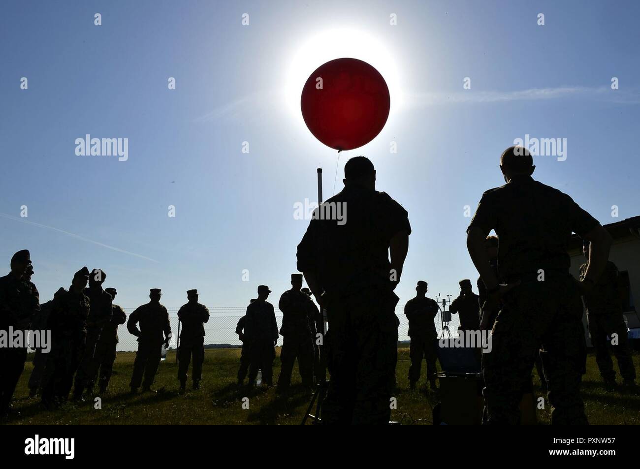 U.S. Airmen and NATO service members gather around a weather balloon at ...