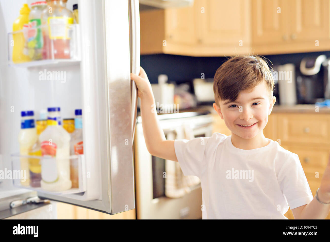 Young white boy standing in front of open refrigerator Stock Photo - Alamy