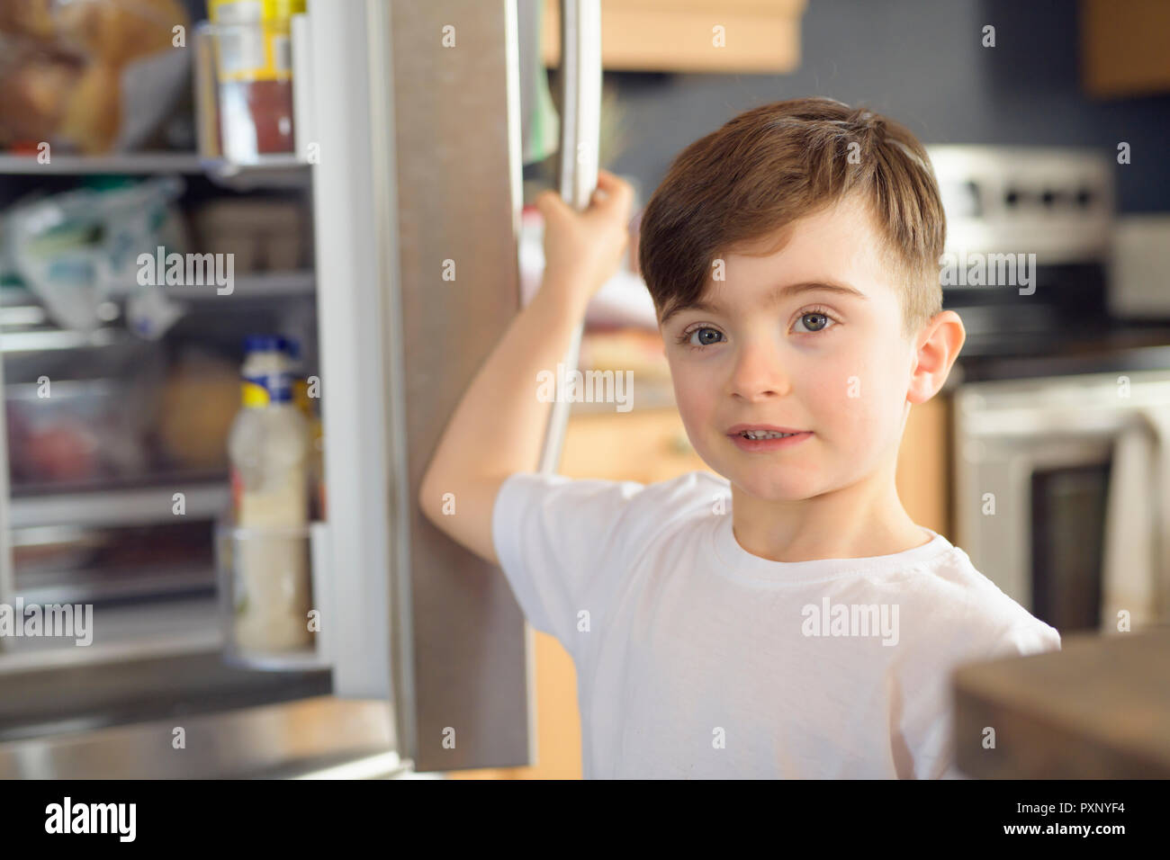 Young white boy standing in front of open refrigerator Stock Photo - Alamy