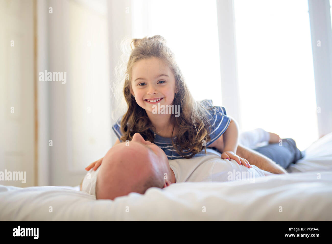 Happy father and daughter having fun together on a bed Stock Photo - Alamy