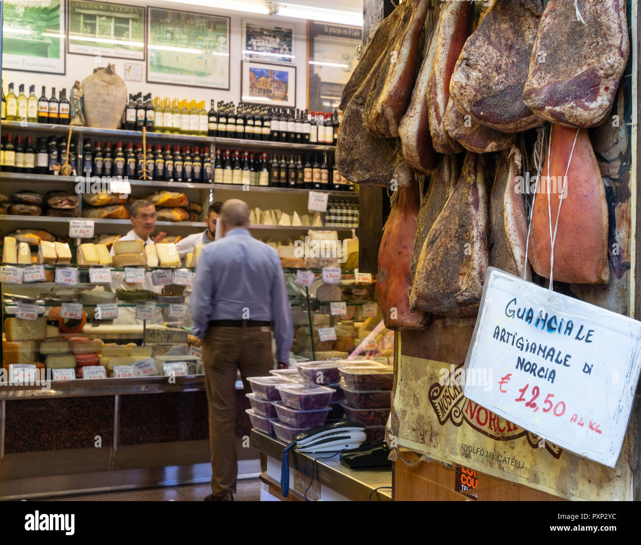 Hams hanging in the doorway and a sign advertising Guanciali, pork ...