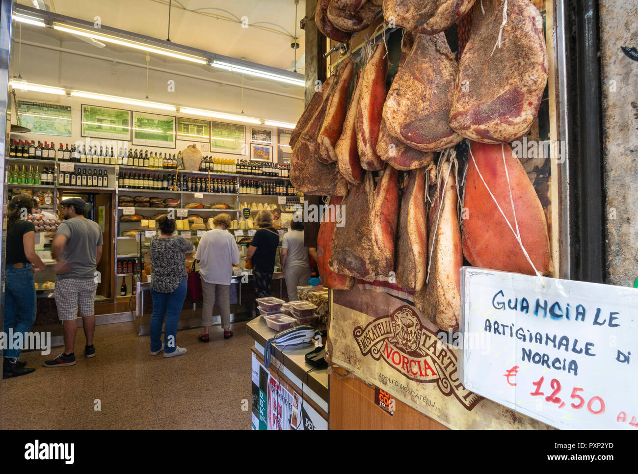 Hams hanging in the doorway and a sign advertising Guanciali, pork ...