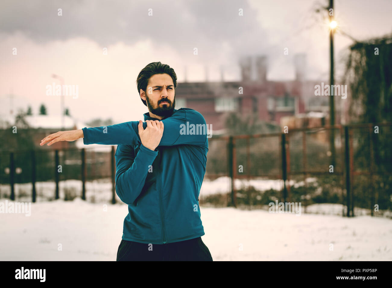Active young man stretching and doing exercises in the old factory ...