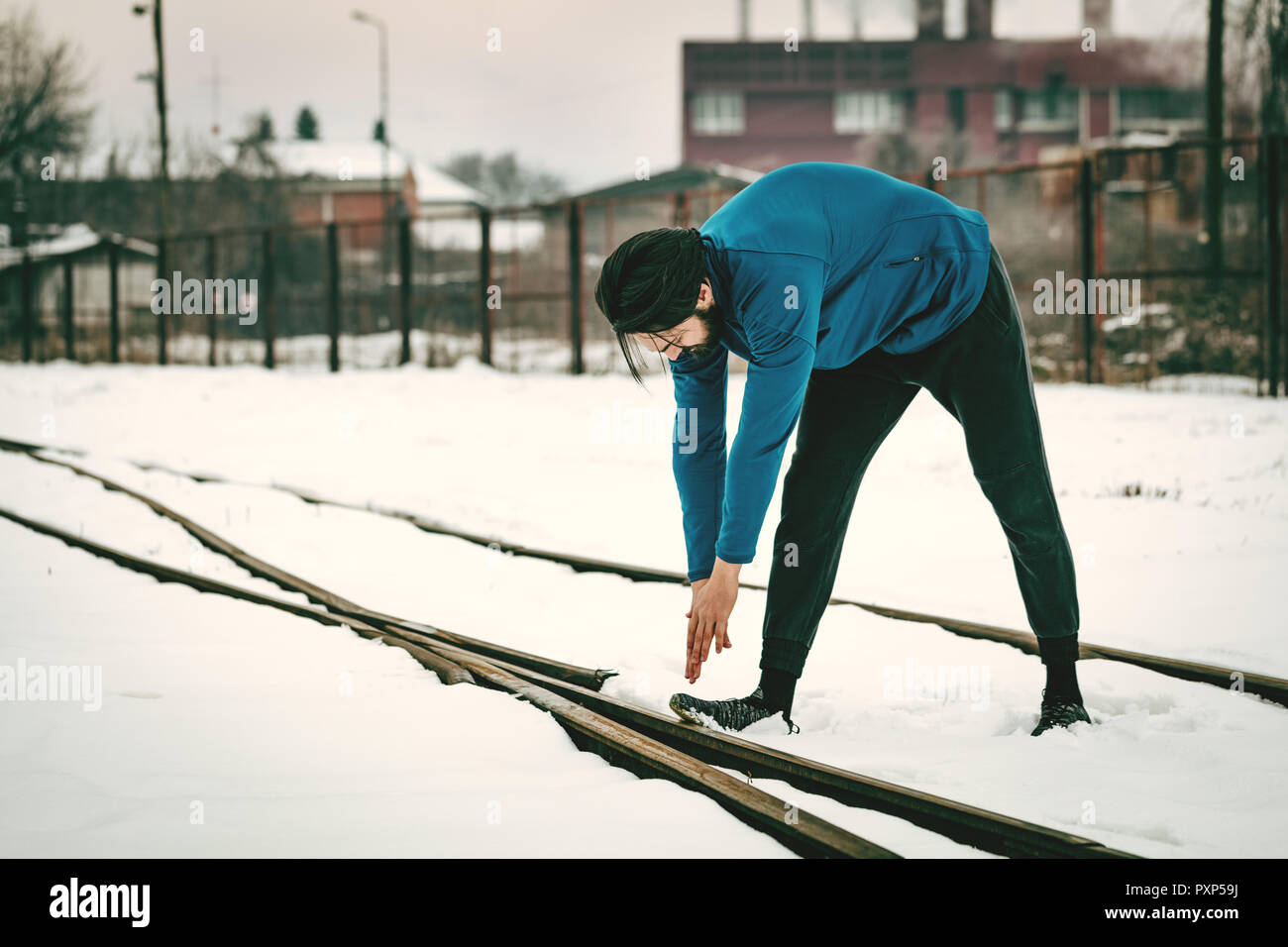 Active young man stretching and doing exercises in the public place ...
