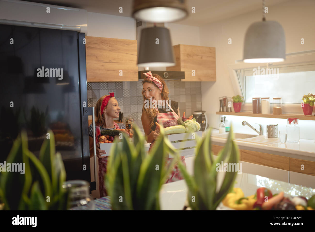 Mother and daughter bring crates full of vegetables into kitchen ...