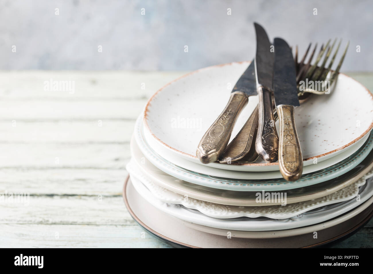 Stack of clean dinner plates with cutlery on top over wooden table ...