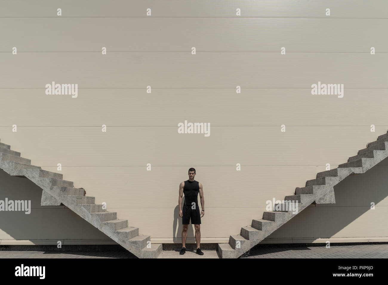 Strong athletic man is standing between two stairs that go to different ...