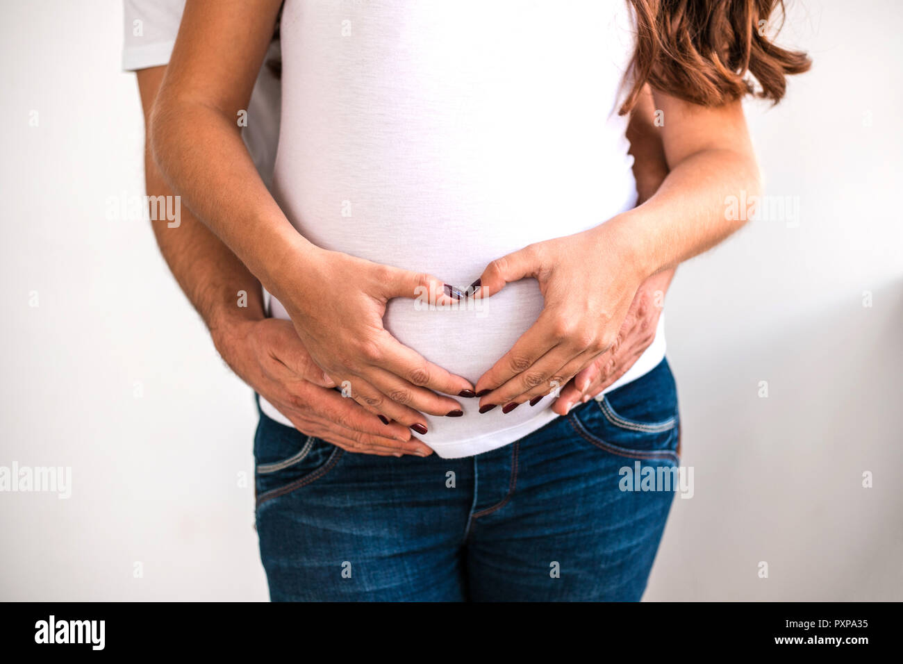 Happy parents hug and making heart shape on pregnant belly. Concept of ...