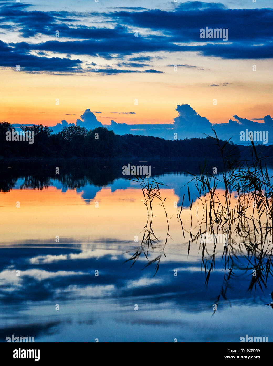 Blue and orange sunset clouds with the setting sun, clouds reflextion ...