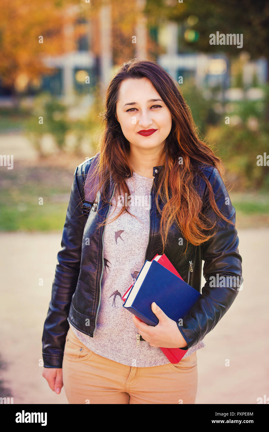 Outside portrait of young female student carry books in the college ...