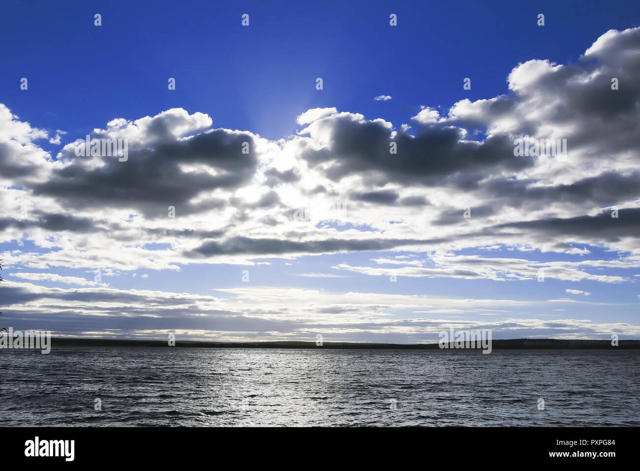Dark clouds and moon loooking through the clouds leaving a path on sea ...
