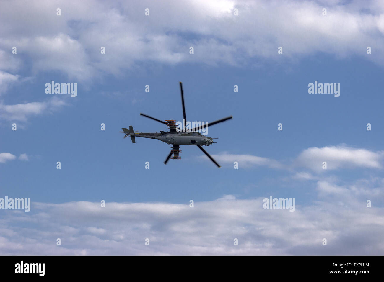 Combat helicopter on blue sky with white clouds. View from the bottom ...