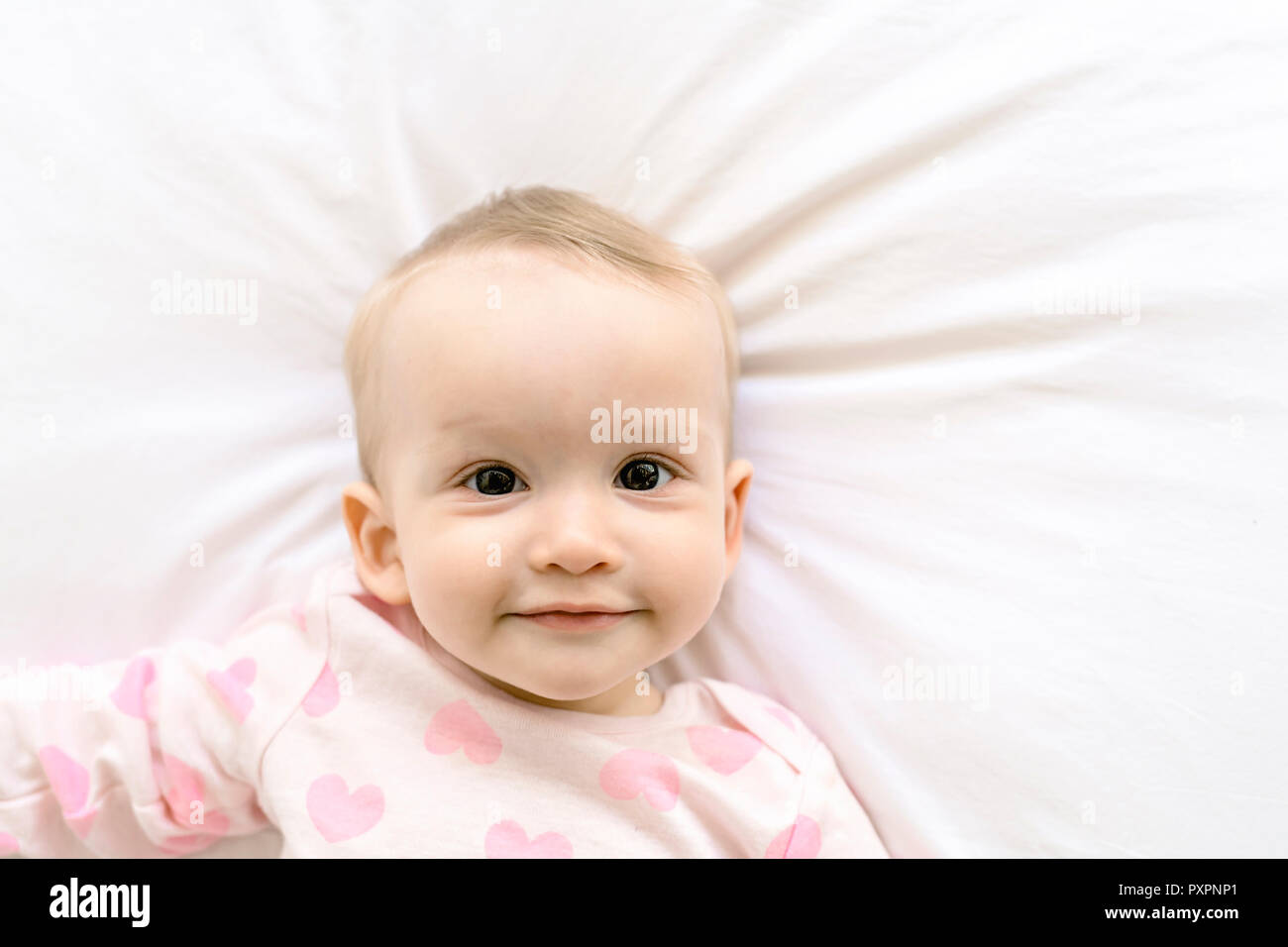 Adorable baby girl cover with white sheet wearing pink clothes Stock ...