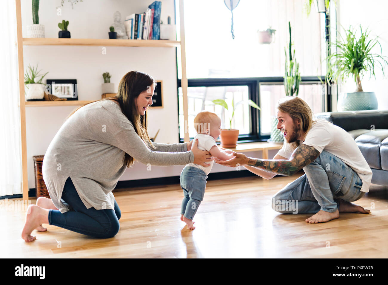 Parent help Baby Daughter Take First Steps At Home Stock Photo - Alamy