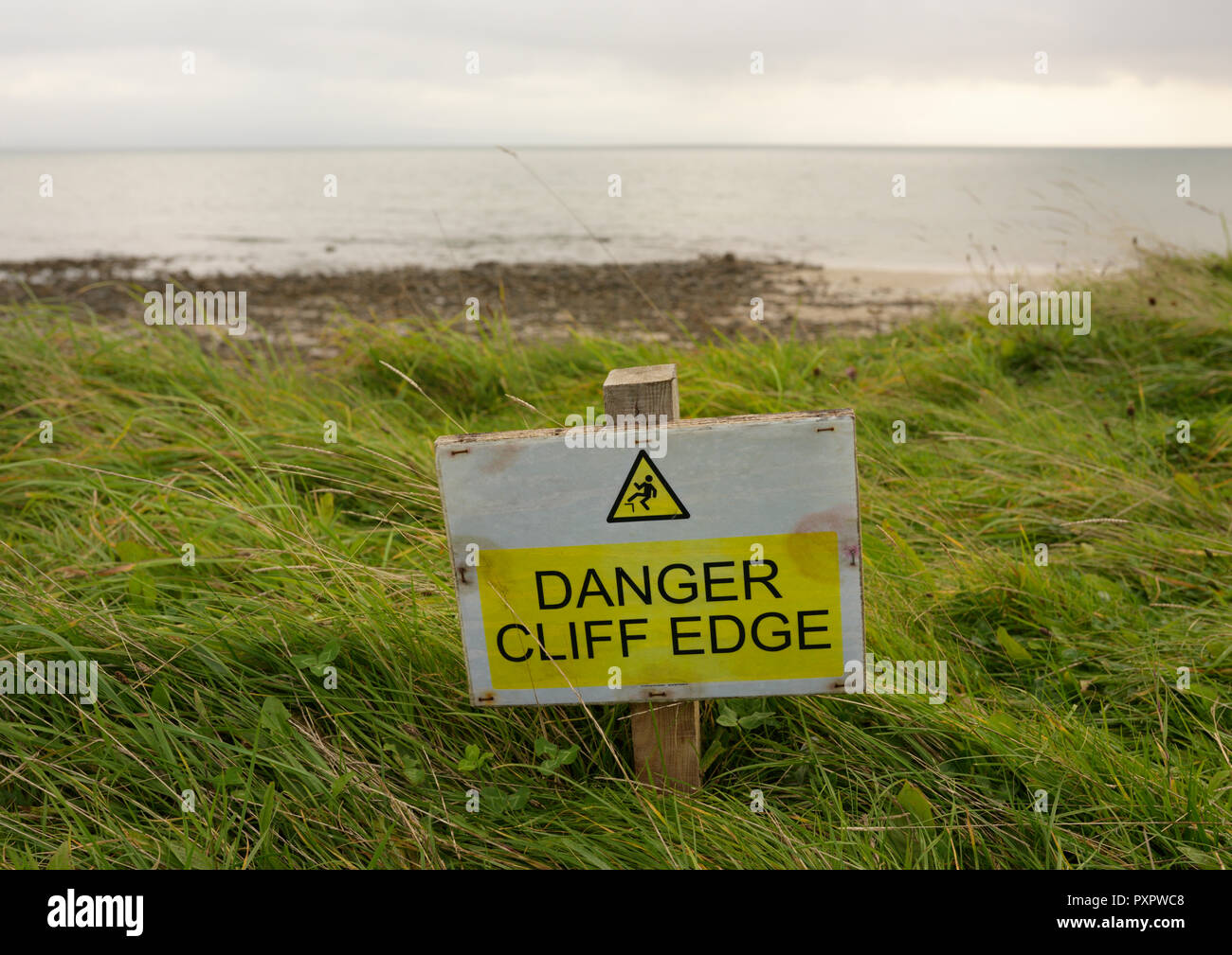 Yellow and white Danger cliff edge warning sign on wales coast path ...