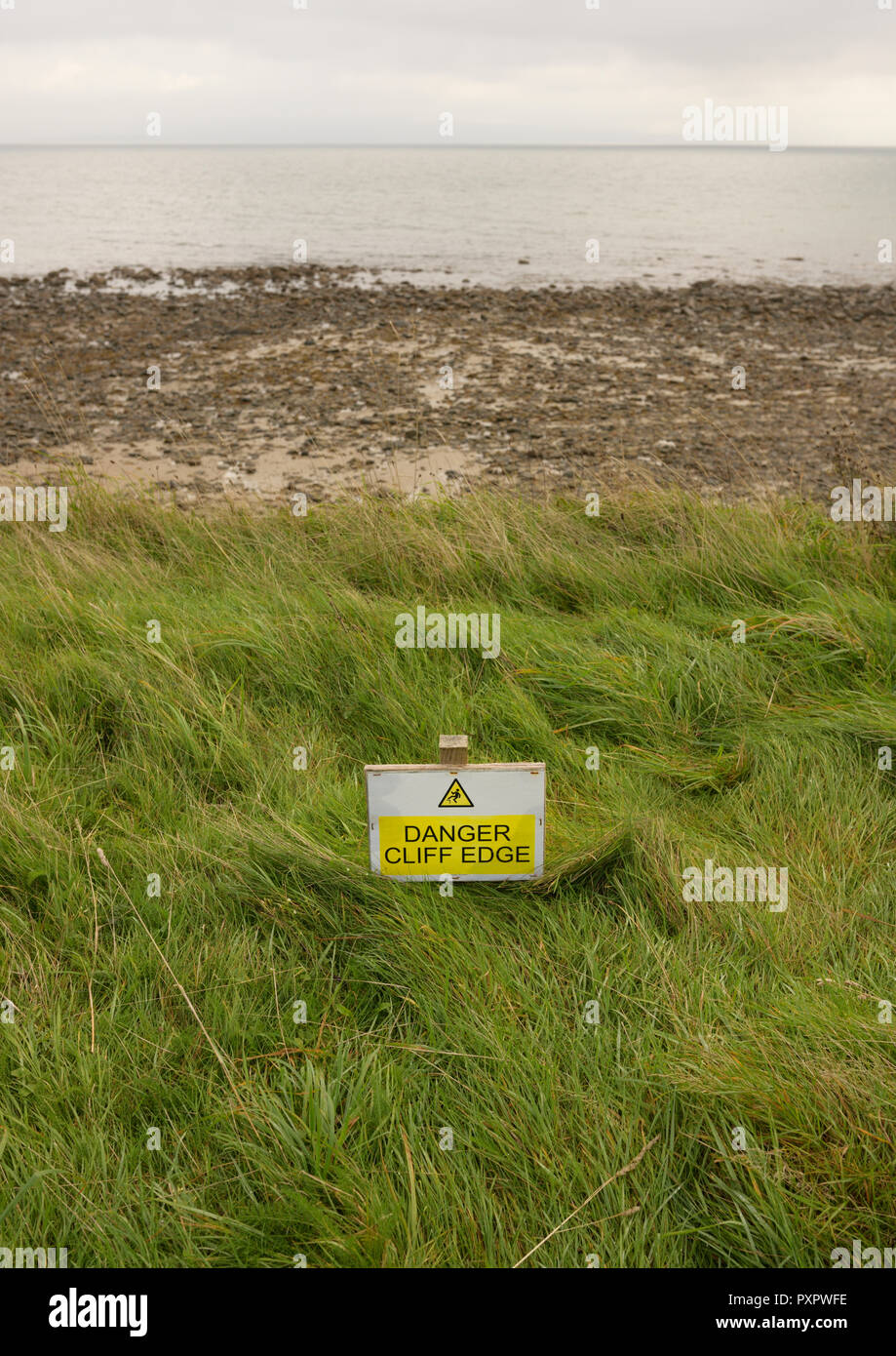 Yellow and white Danger cliff edge warning sign on wales coast path ...