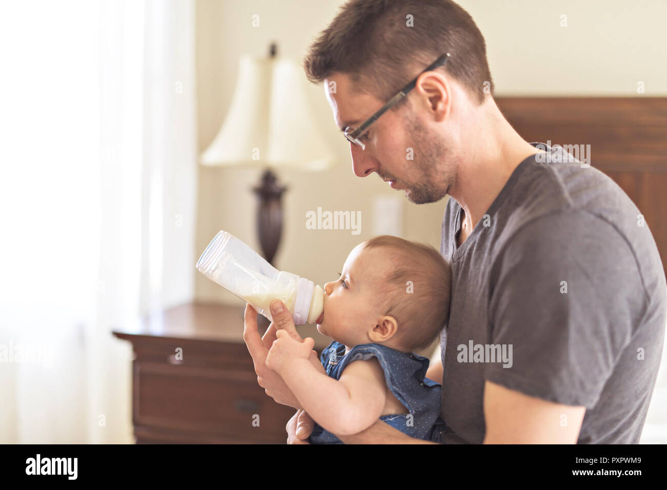 man feeding milk to baby girl at home Stock Photo - Alamy