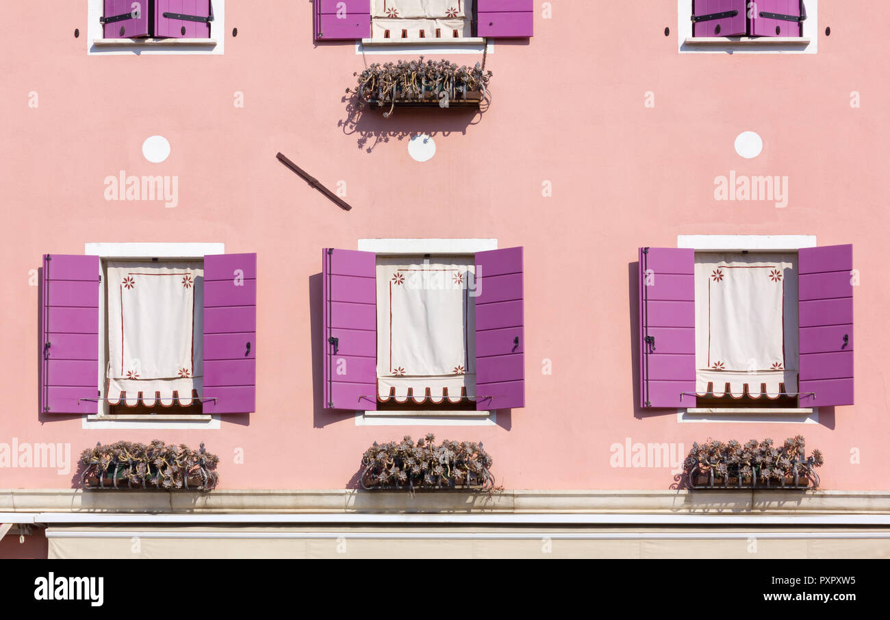 Detail of a decorated pink colored house's exterior with purple window ...