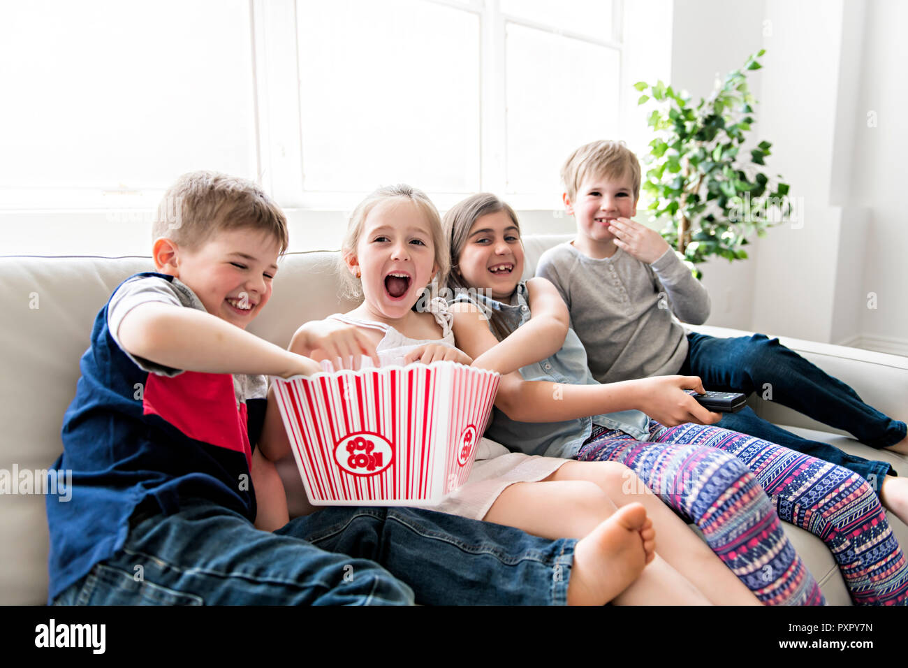child group eating popcorn together on sofa Stock Photo - Alamy