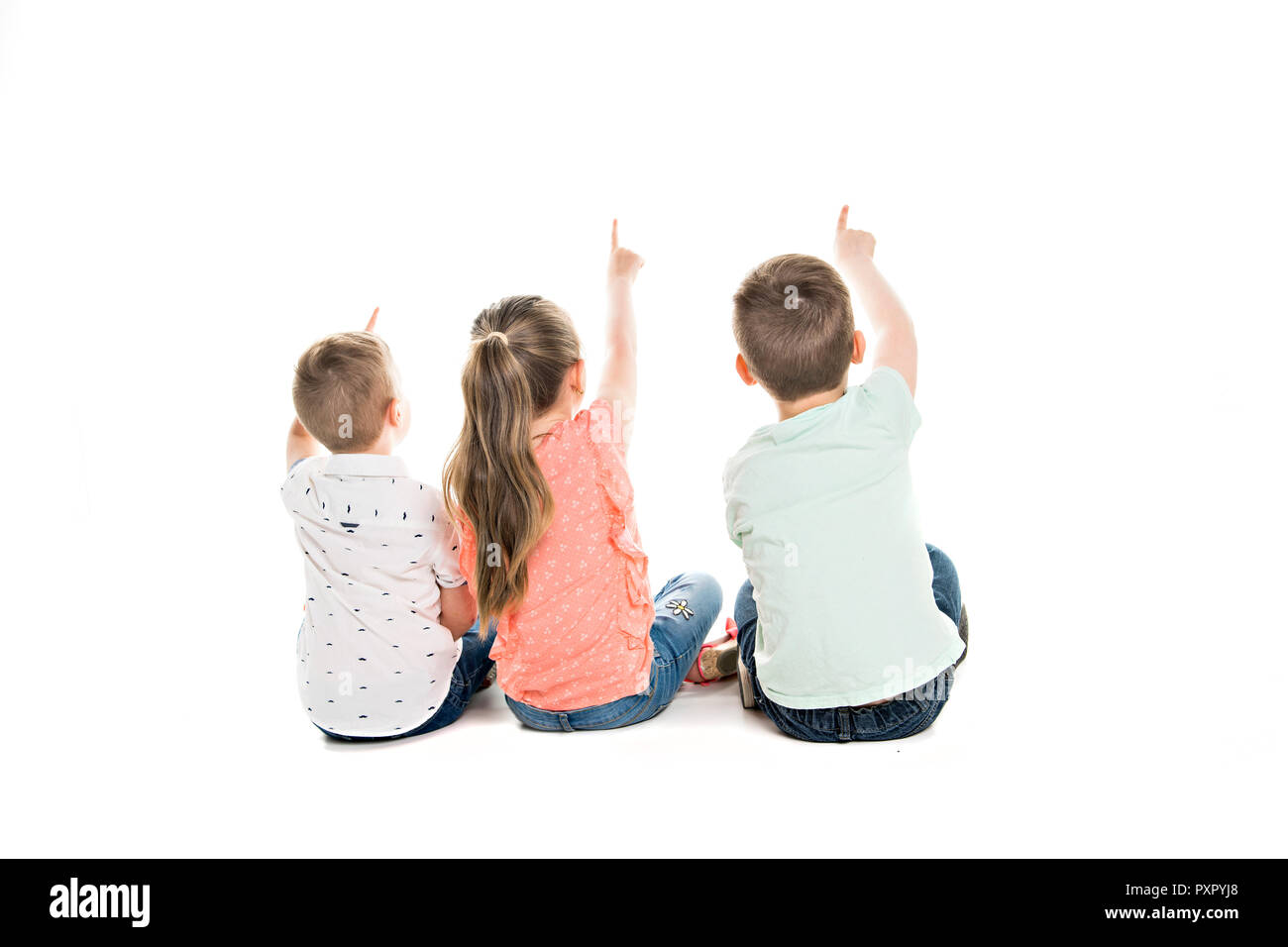 Back view of child group sitting on floor looking at wall Stock Photo ...