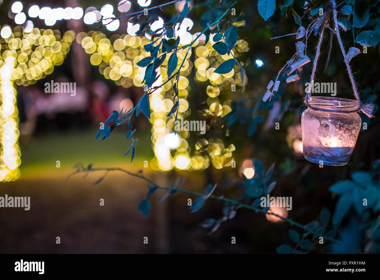 Hanging glasses with candles at night wedding party on garden ...