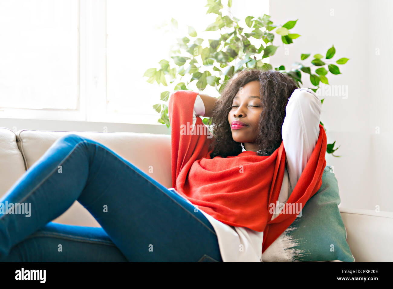 Attractive black young woman relaxing on a sofa at home Stock Photo - Alamy