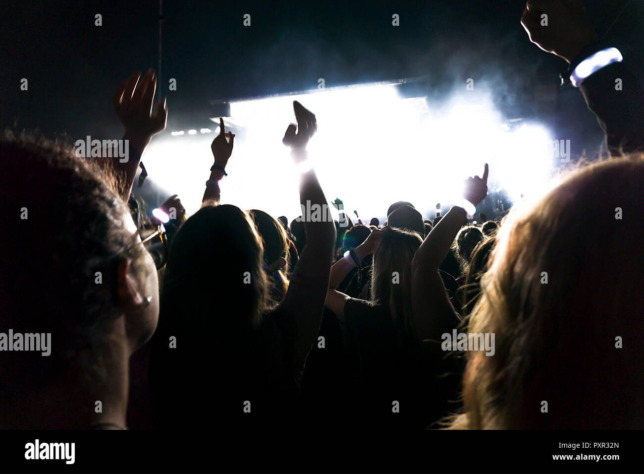 A silhouettes of concert crowd in front of bright stage lights. Dark ...